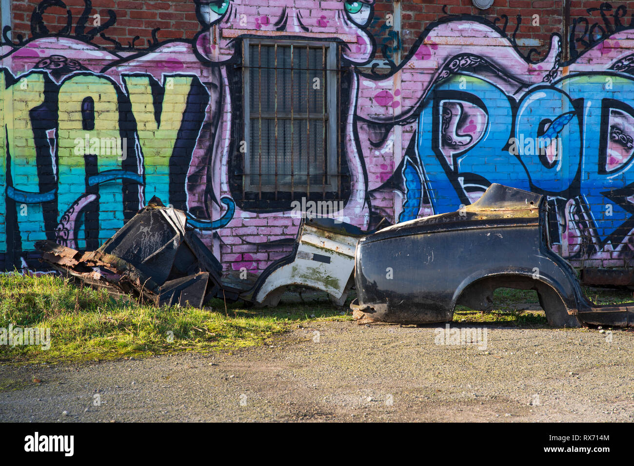 Car wreck in front of a wall with a small piece of graffiti Stock Photo ...