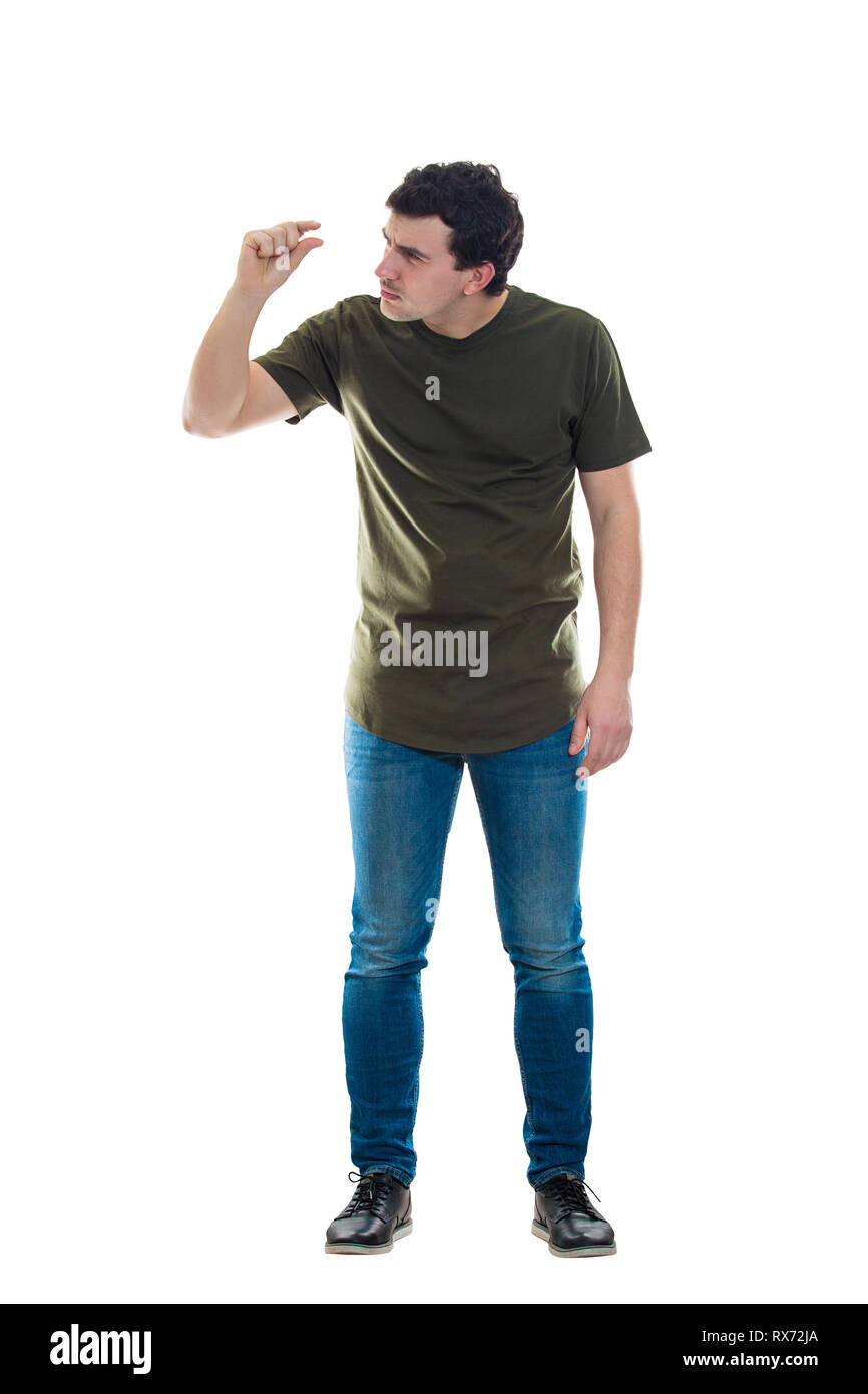 Full length portrait perplexed young man holding something tiny between ...