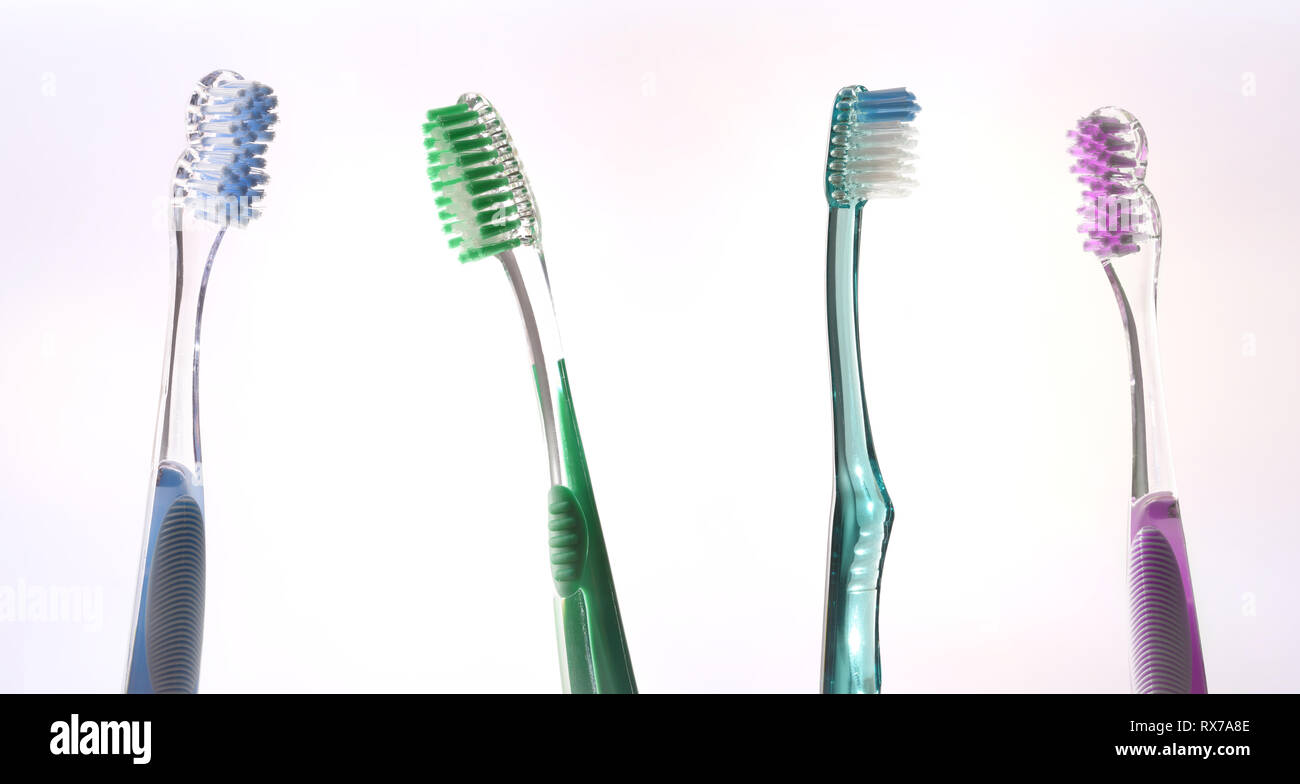 Four colorful transparent tooth brushes on pink and blue gradient ...