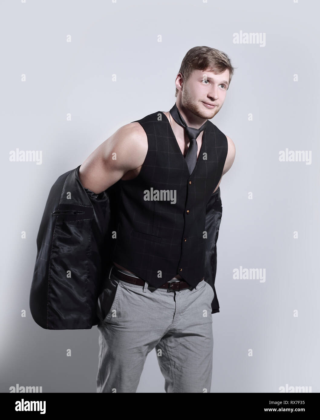 young businessman in a business suit without a shirt holds a jacket ...
