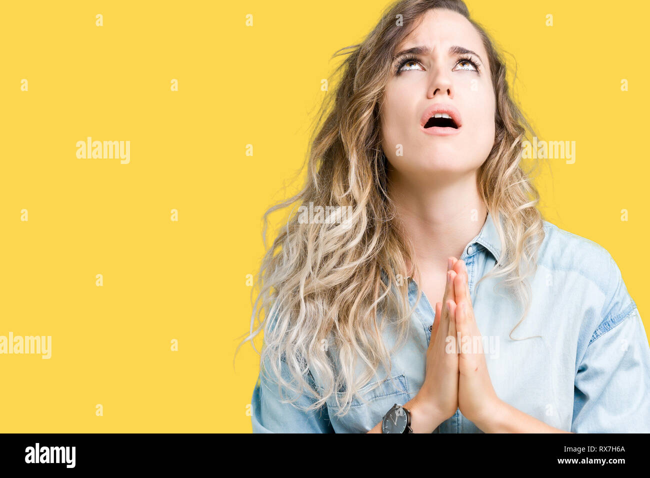 Beautiful young blonde woman over isolated background begging and ...