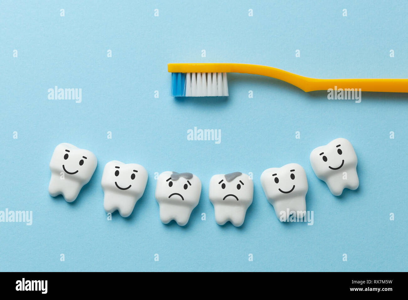 Healthy white teeth are smiling and tooth with caries is sad on blue ...
