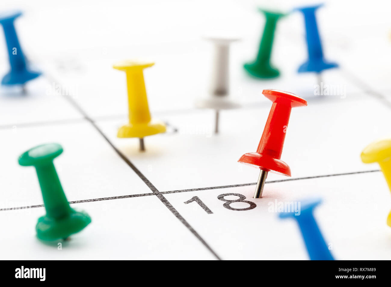 Colored push pin on white calendar background Stock Photo - Alamy