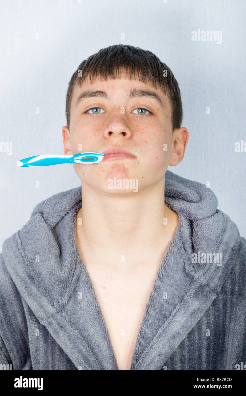 Teenage caucasian boy cleaning his teeth in the morning wearing a ...