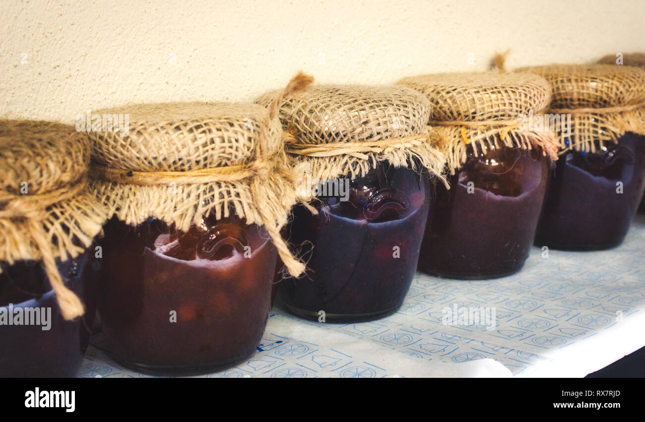 Glass jars of varied jams covered with sackcloth and tied with string ...