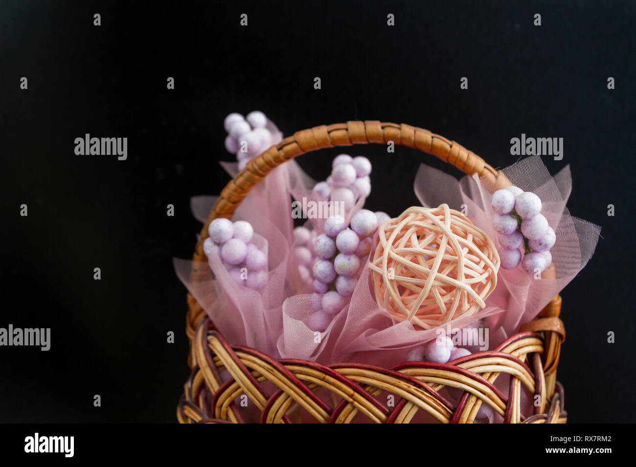 Spring straw basket with pink decorations and roundels on black ...