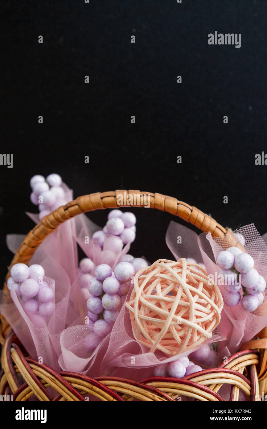 Spring straw basket with pink decorations and roundels on black ...