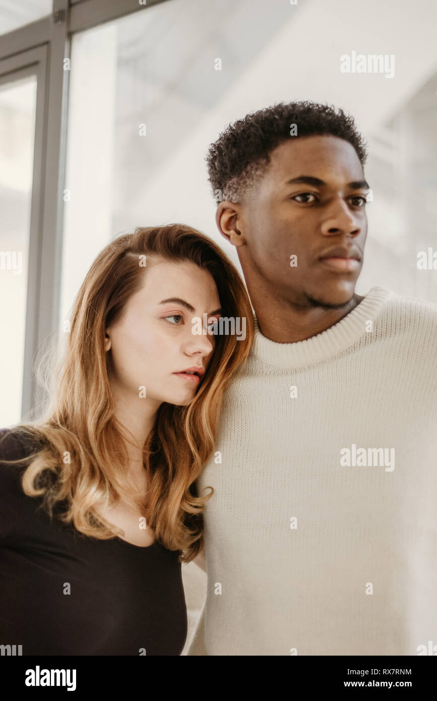 A good looking and young couple poses with next to each other and look ...