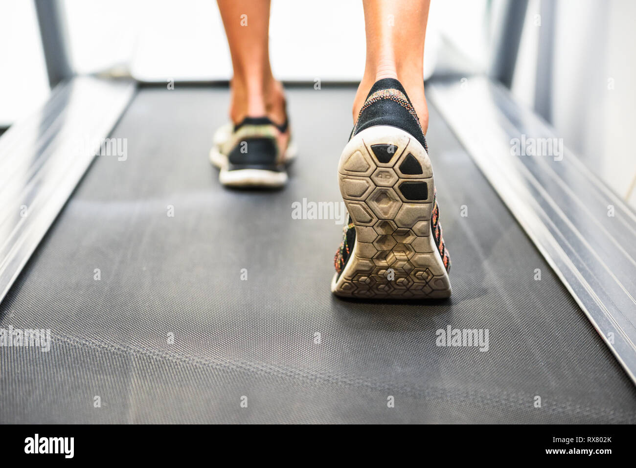 Male muscular feet in sneakers running on the treadmill at the gym ...