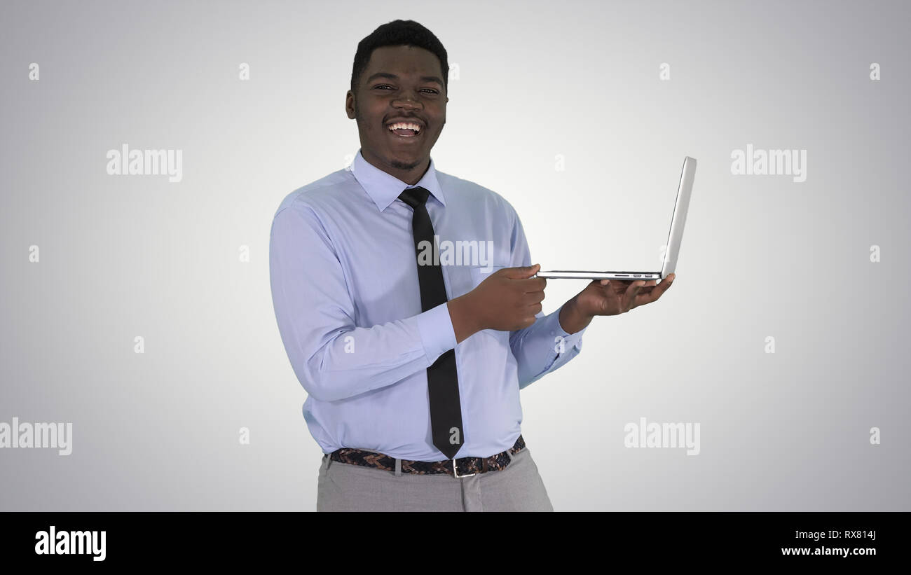 Medium shot. Talking to camera young african man with laptop in his ...