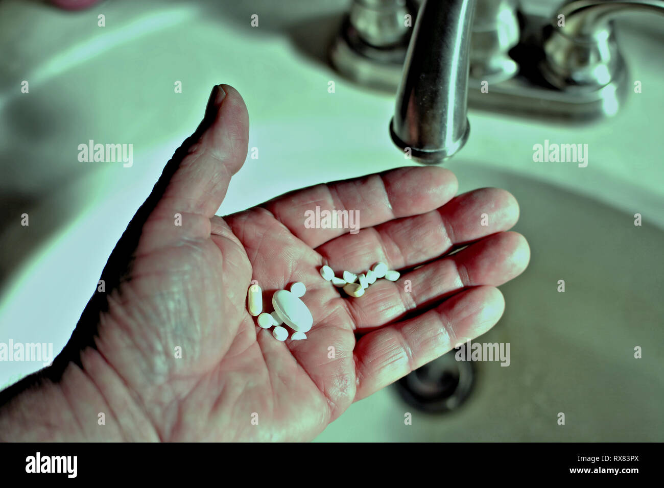 A closeup of a senior's hand ready to throw his pills down the drain ...