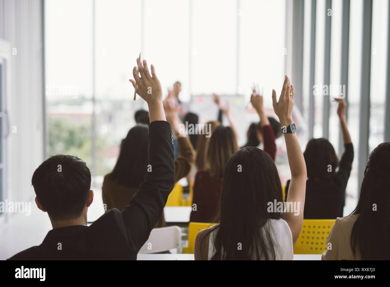 Raised up hands and arms of large group in seminar class room at ...