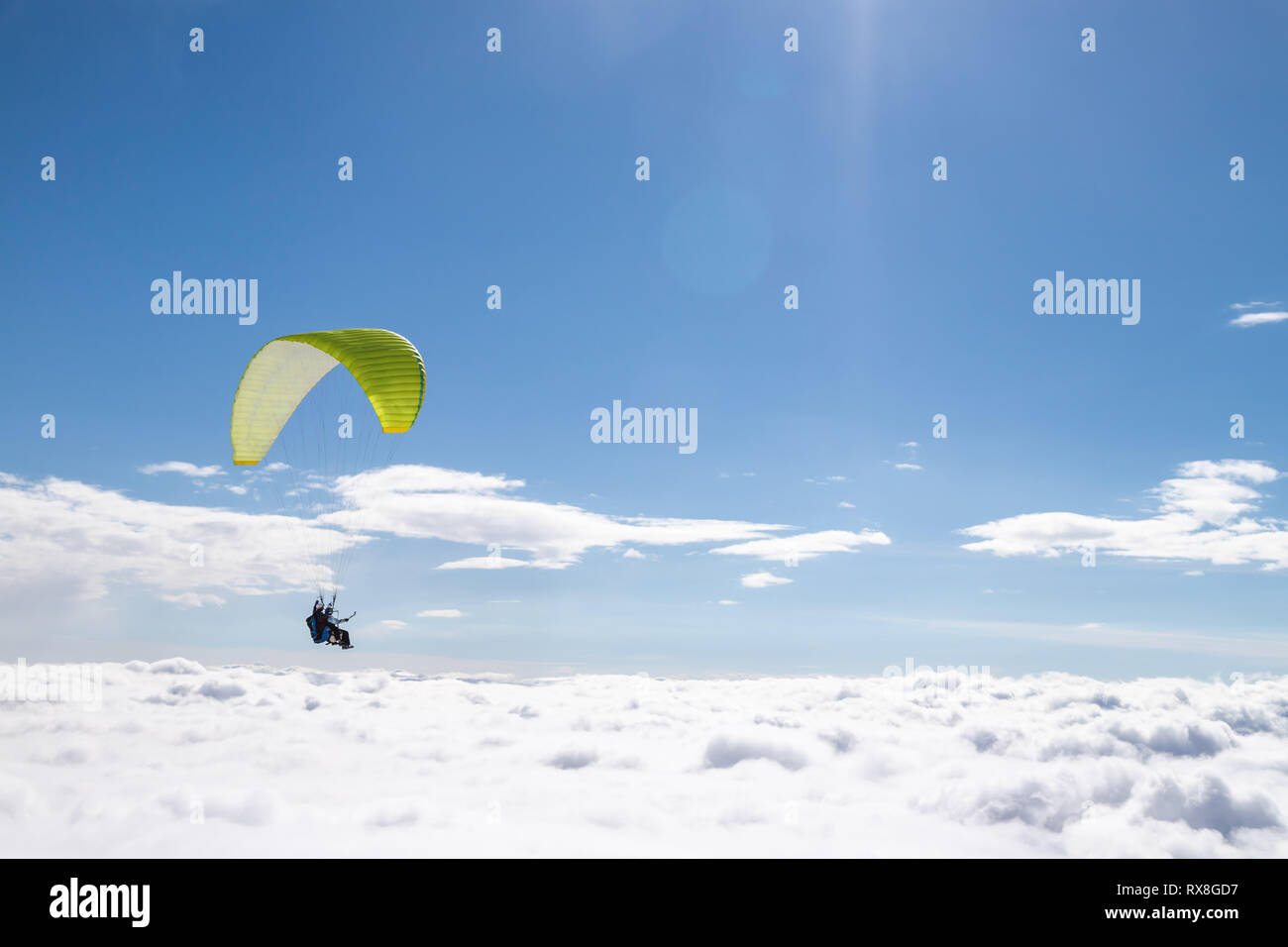 Paragliding at snowy mountains over ski resort at sunny winter day ...