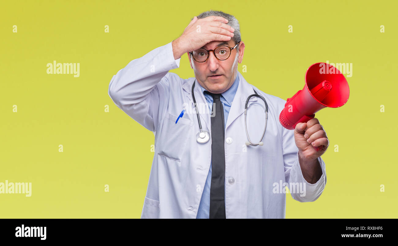 Handsome senior doctor man yelling through megaphone over isolated ...