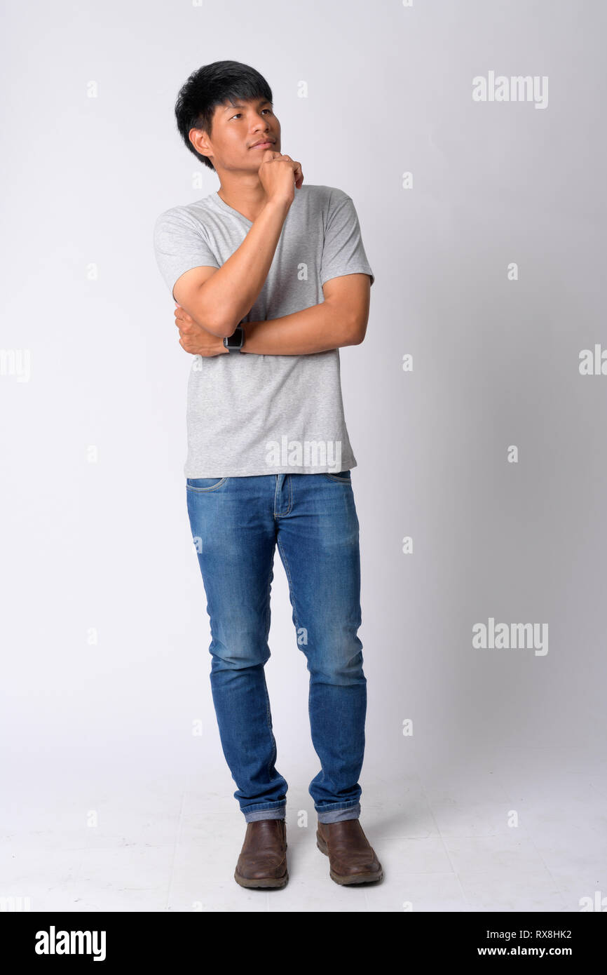 Full body shot of young Asian man thinking Stock Photo - Alamy