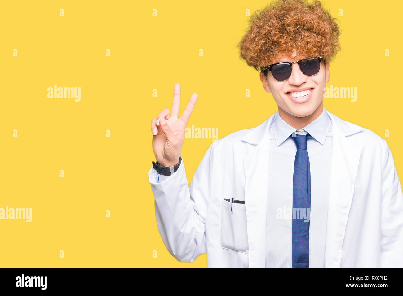 Young handsome scientist man wearing professional coat and sunglasses ...