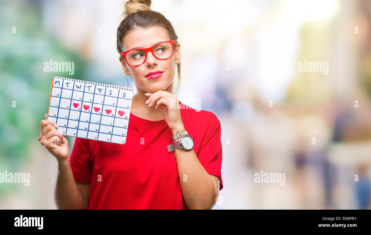 Young beautiful woman holding menstruation calendar over isolated ...