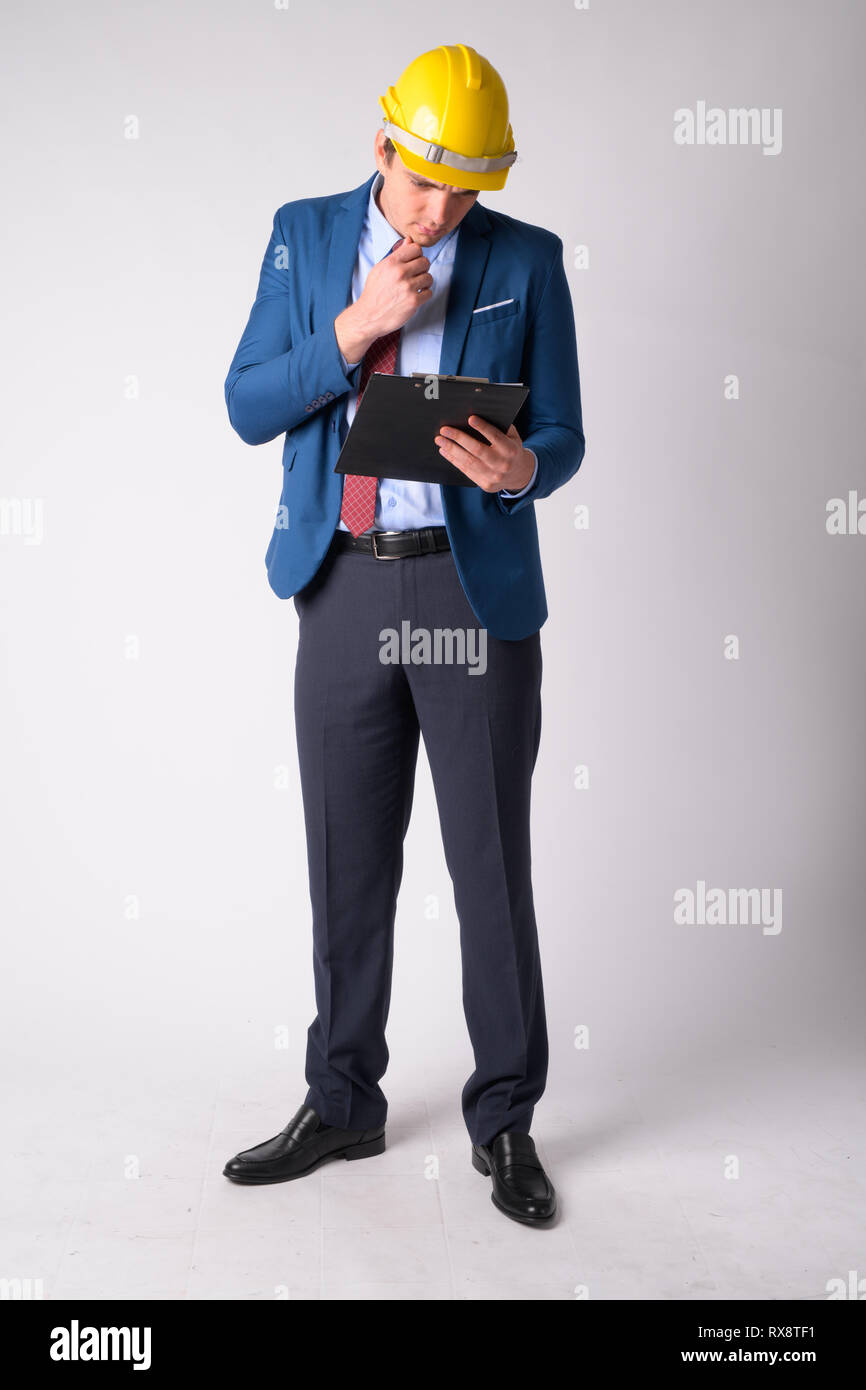 Full body shot of businessman as engineer thinking while reading on ...