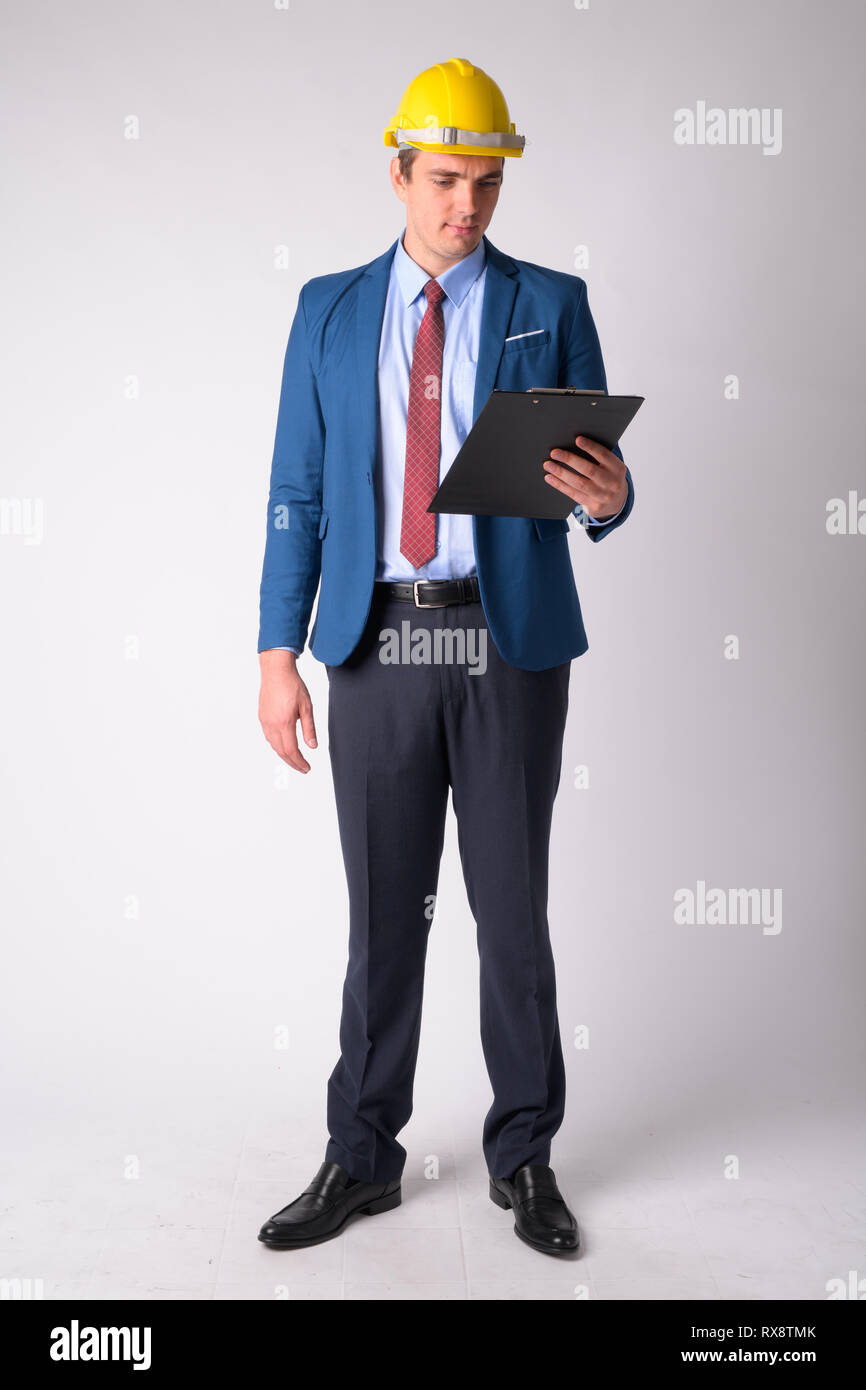 Full body shot of businessman as engineer reading on clipboard Stock ...