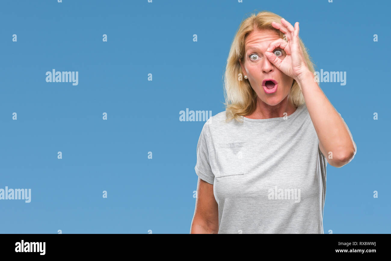 Middle age blonde woman over isolated background doing ok gesture ...