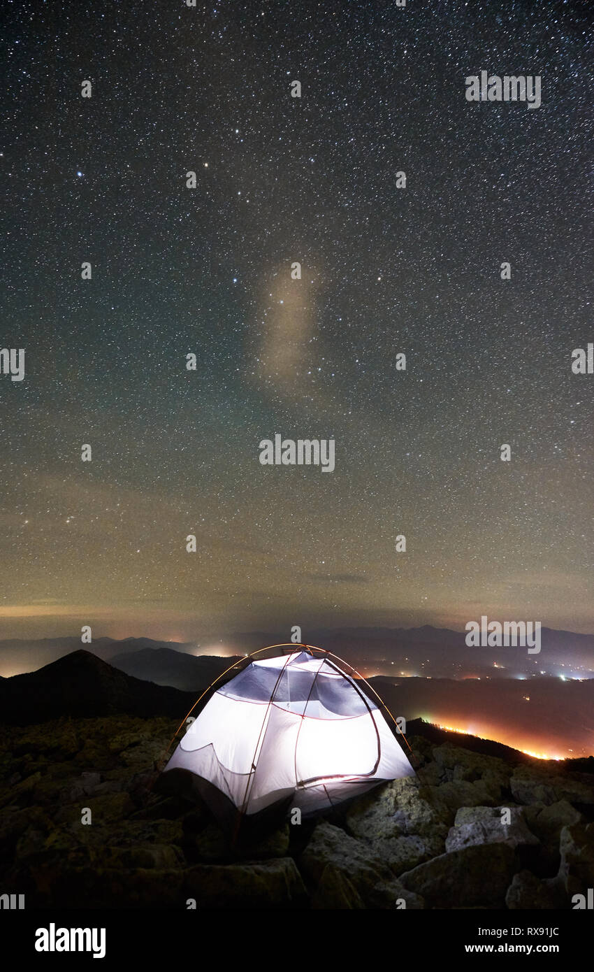 Tourist camp at summer night on the top of rocky mountain. Illuminated ...