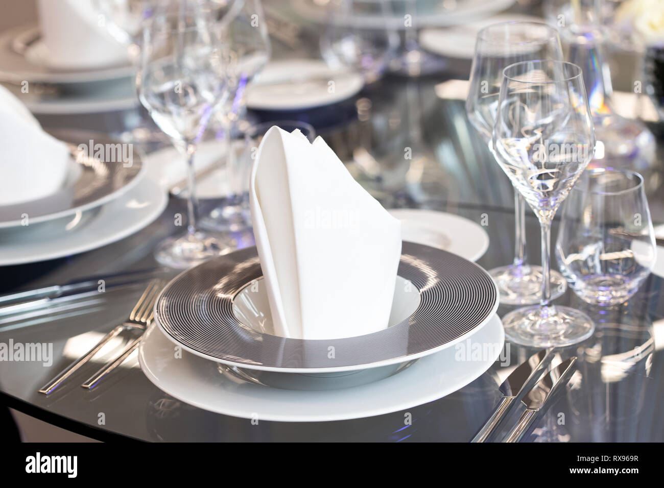 Detail of black and white modern banquet setting on glass table. Blurry ...