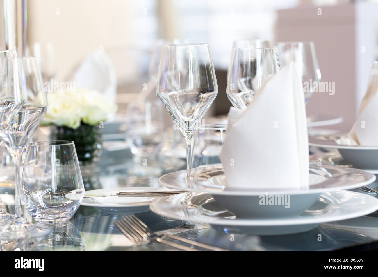 Detail of modern banquet setting on glass table. Blurry background ...