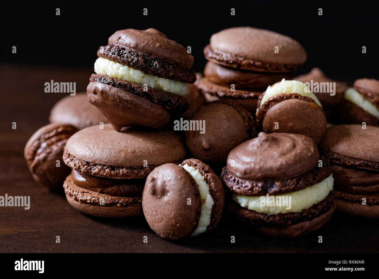 Chocolate macarons of various sizes. Brown background Stock Photo - Alamy