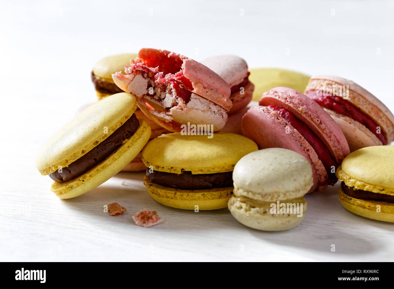 Macarons of various colors and sizes. One half eaten. White background ...