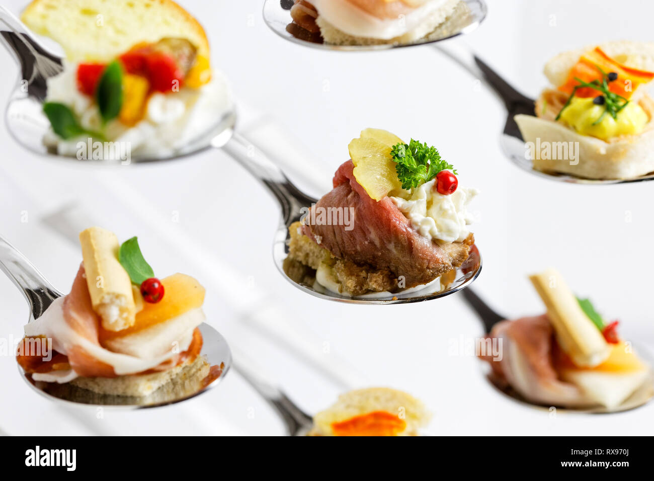 Closeup of mixed canapes on metal spoons. White background Stock Photo ...