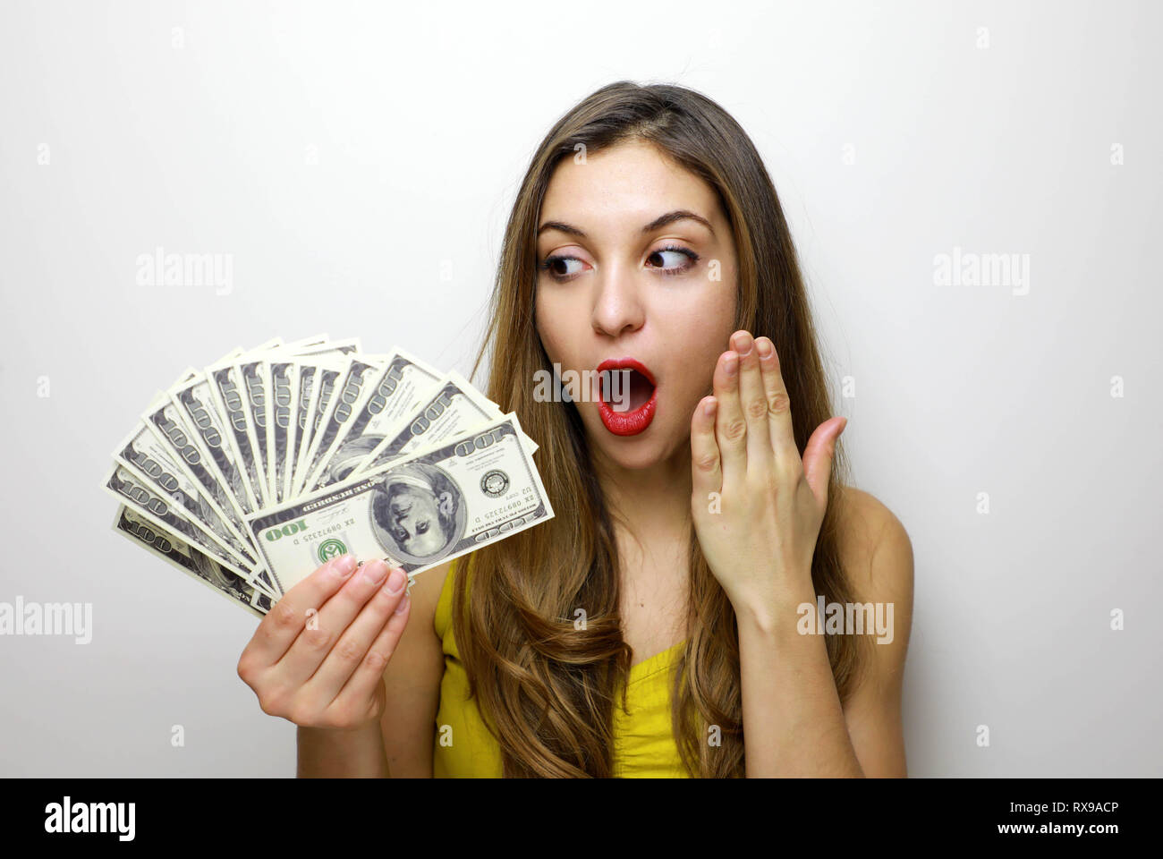 Portrait of a shocked pretty girl looking at bunch of money banknotes ...