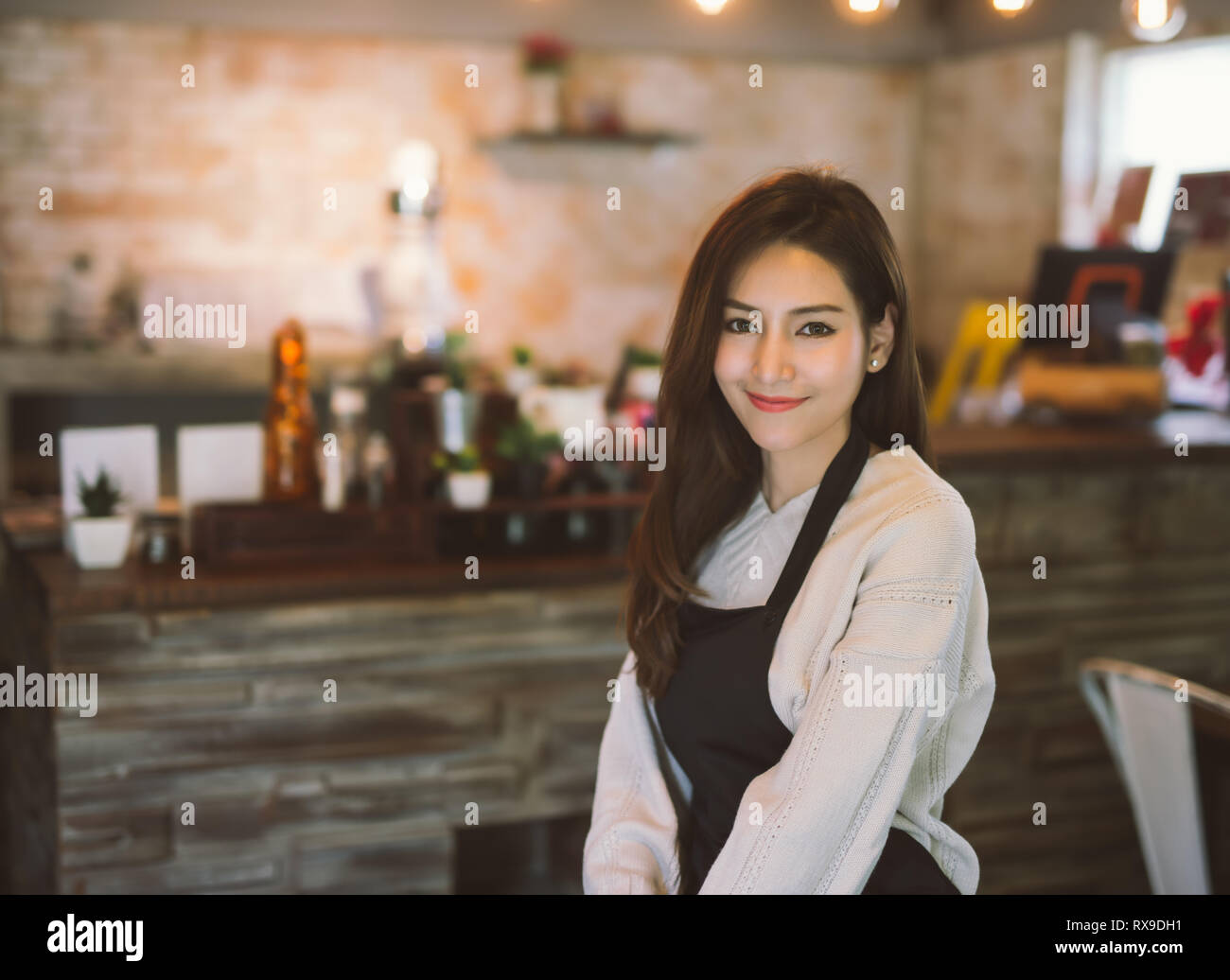 Portrait of Asian girl waitress wearing apron and standing in coffee ...