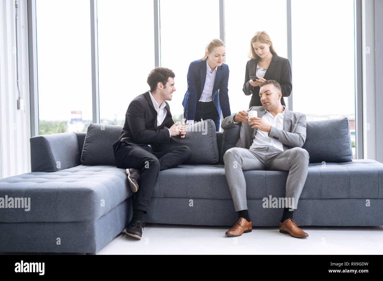 business people taking to each other on sofa in office Stock Photo - Alamy
