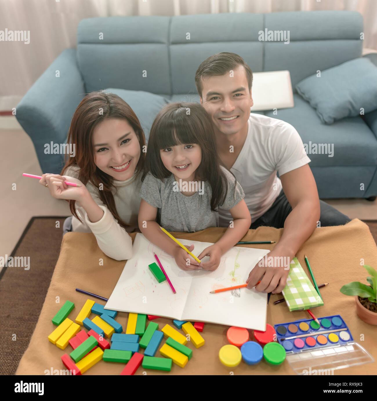 Portrait of happy family daughter and parent drawing and reading ...