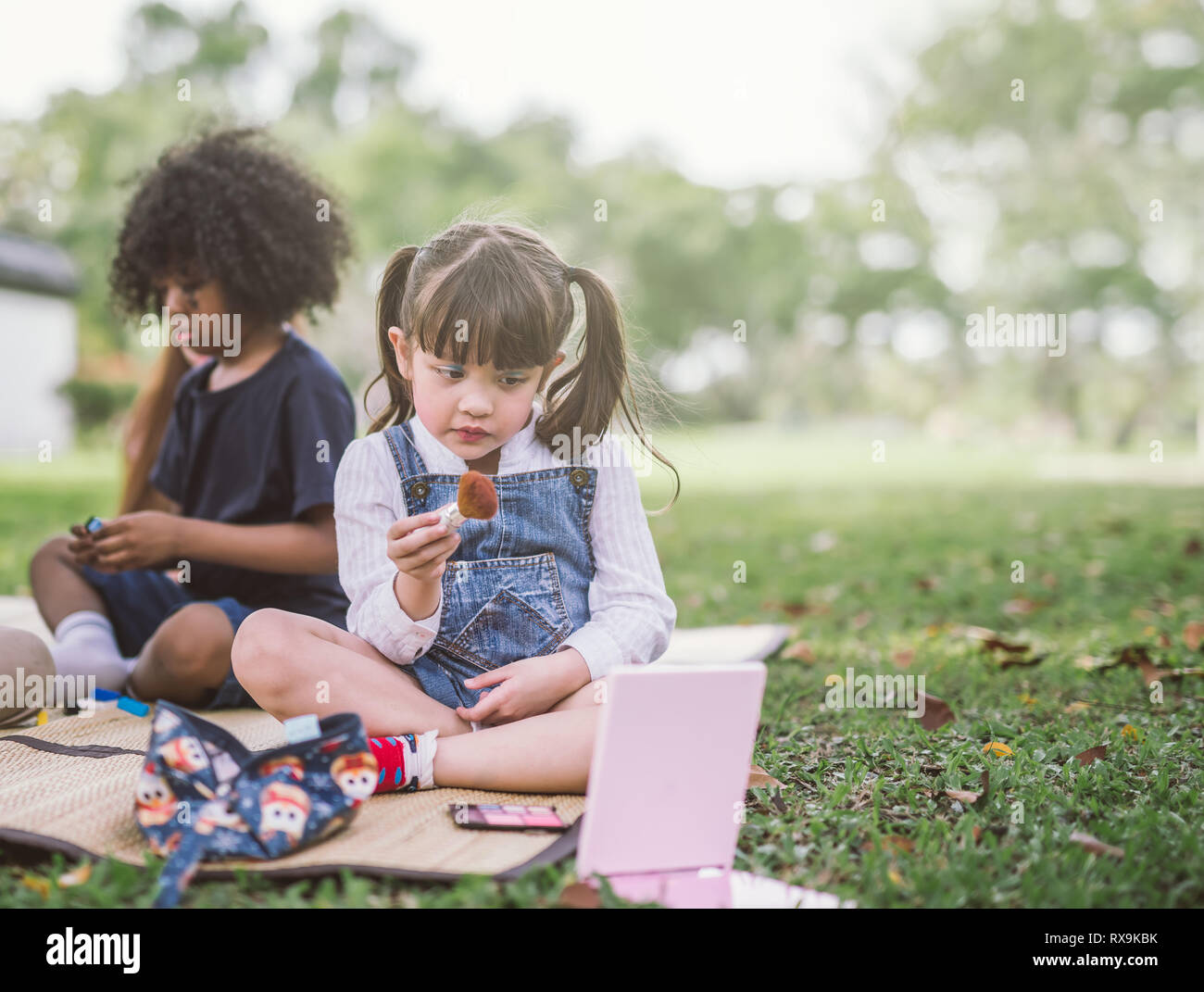 Child cosmetics. Little girl playing applying make up Stock Photo - Alamy