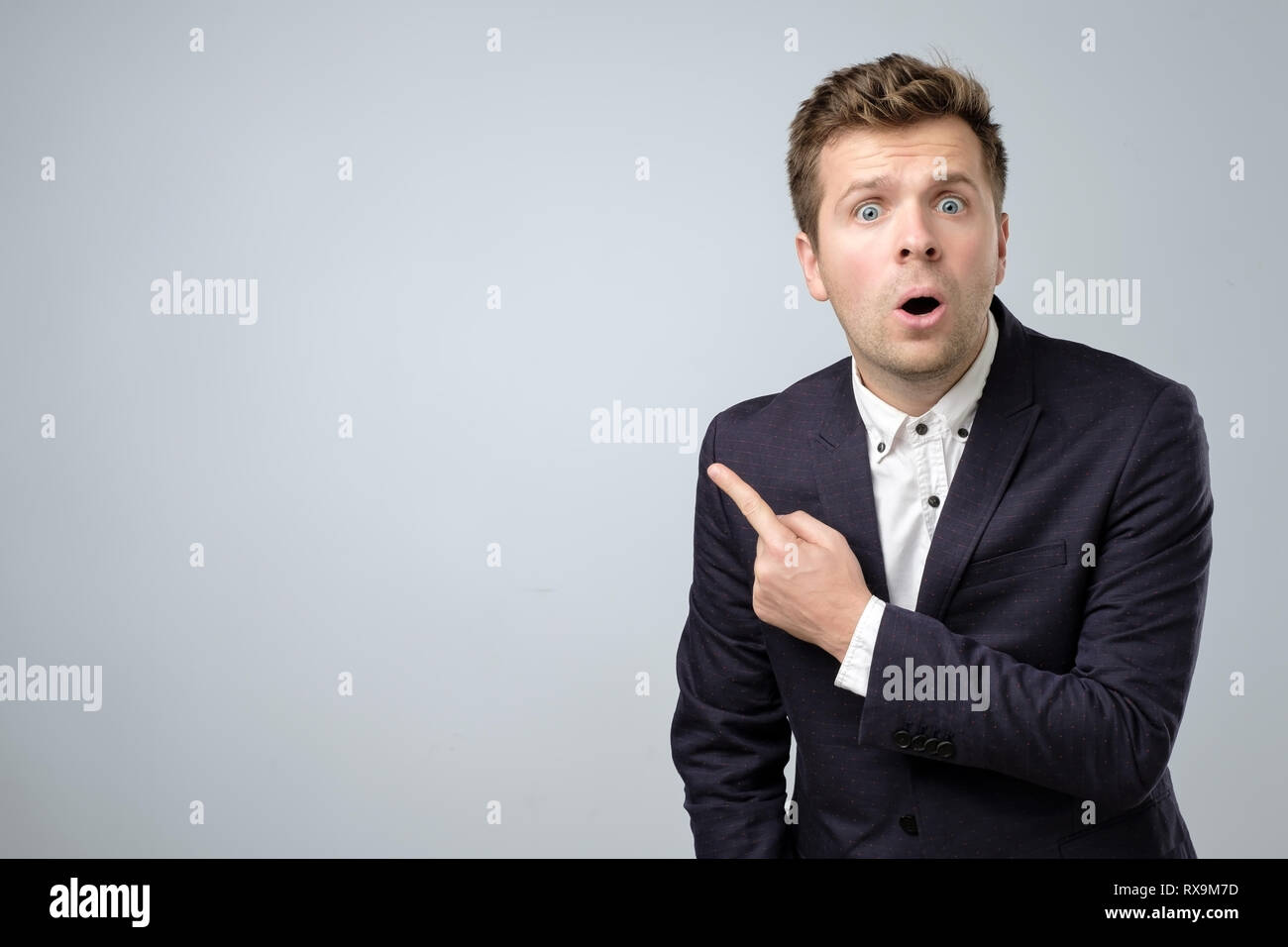 Funny man pointing finger at copy space . He is confused with news ...