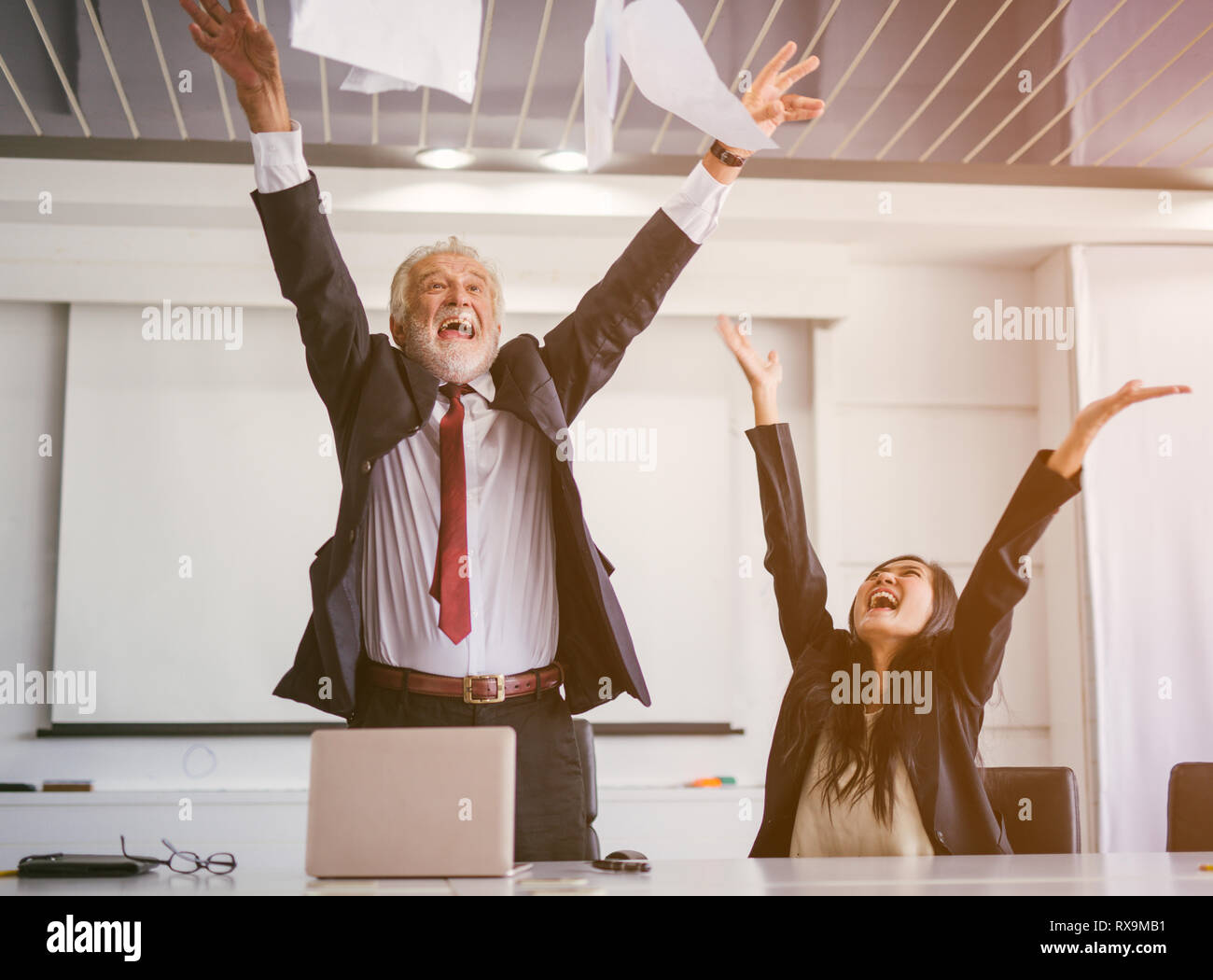 Celebrating success. two business people throwing documents and looking ...