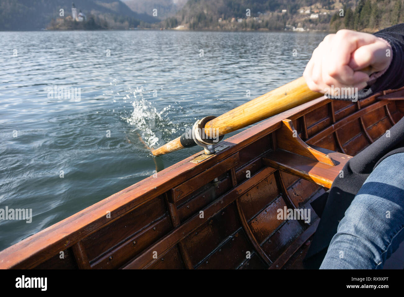 Young woman using paddle on a wooden boat with island Bled behind it ...