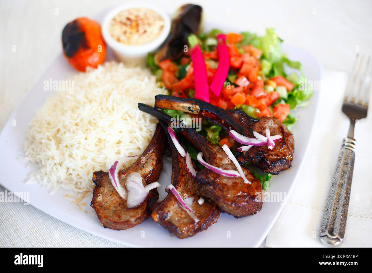 Close-up of lamb chops with salad and rice served in plate on table ...