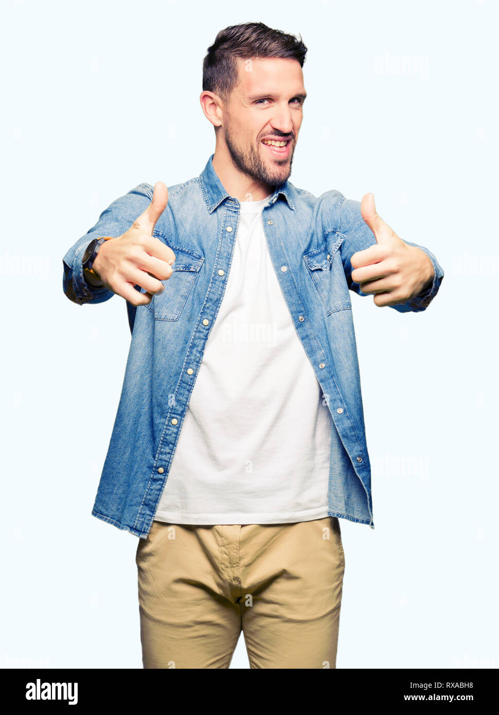Handsome man with blue eyes and beard wearing denim jacket approving ...