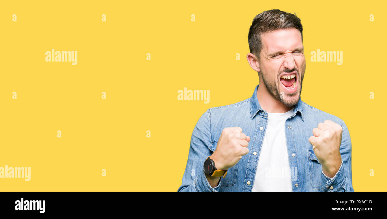 Handsome man with blue eyes and beard wearing denim jacket very happy ...