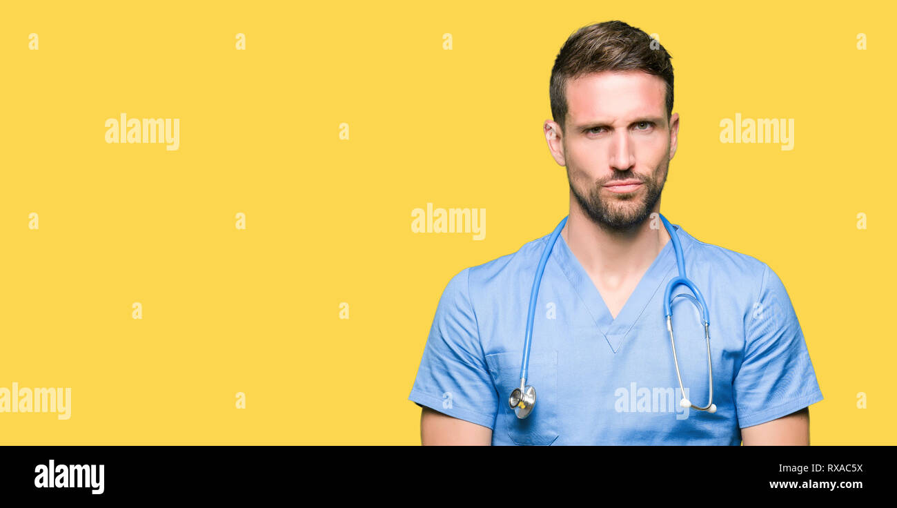 Handsome doctor man wearing medical uniform over isolated background ...