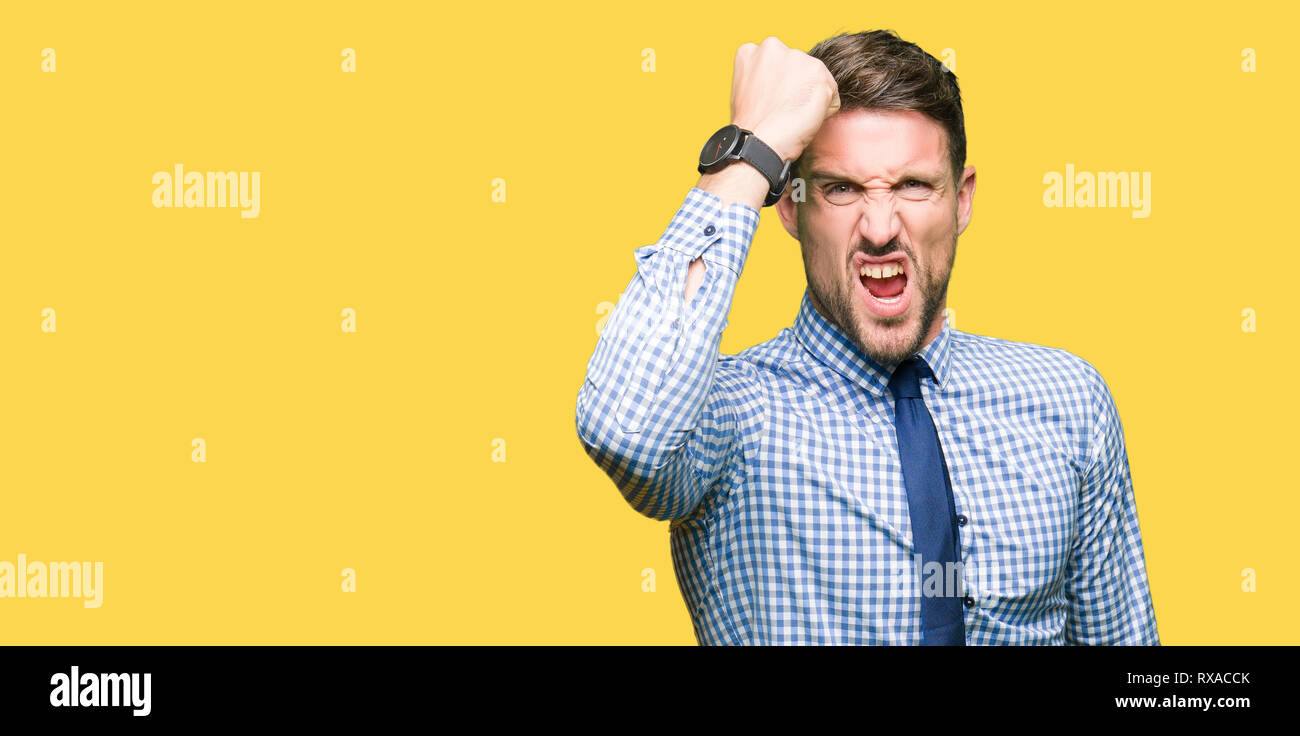Handsome business man wearing tie angry and mad raising fist frustrated ...