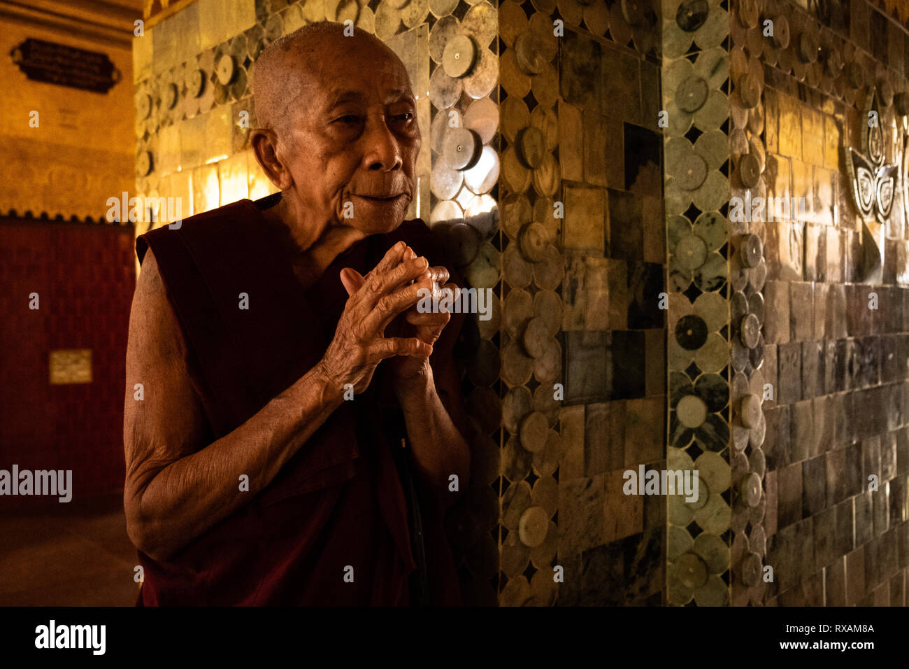 An elderly Buddhist monk praying in the Mahamuni Image complex ...