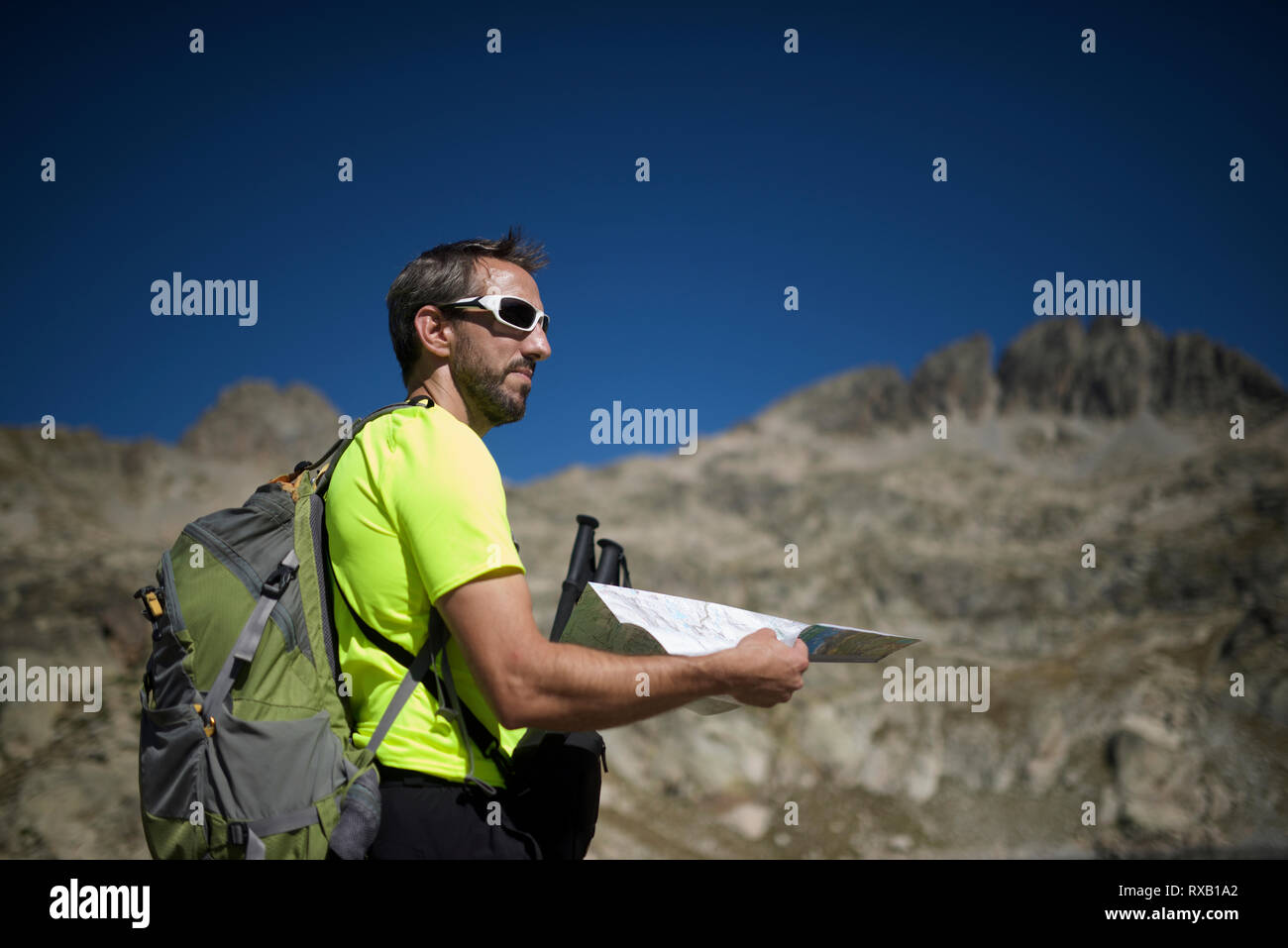 Side view of male hiker holding map while standing on mountain against ...