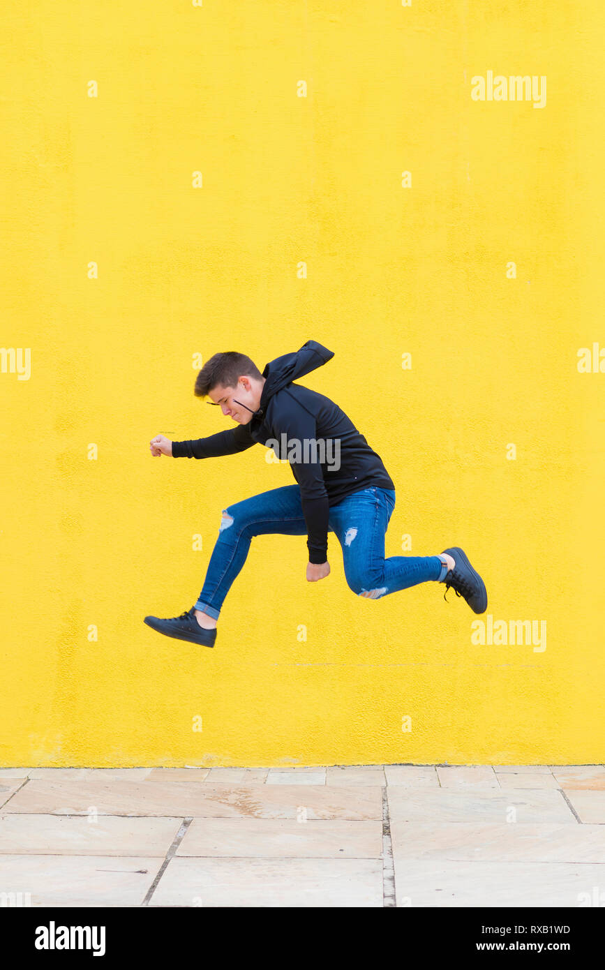 Side view of happy man jumping on sidewalk against yellow wall Stock ...
