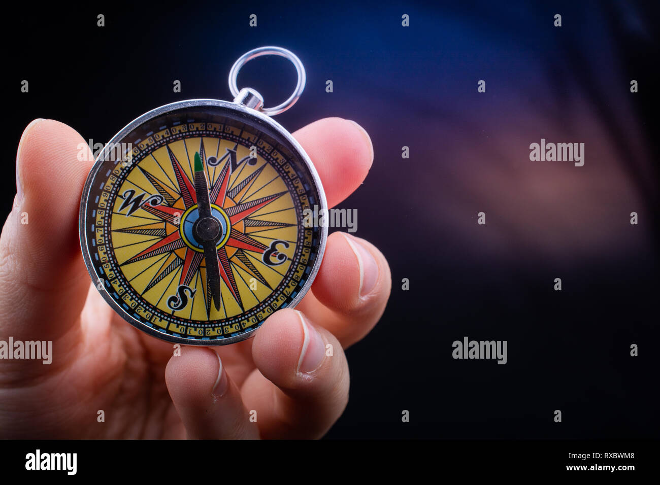 Hand is holding a magnetic compass on black background Stock Photo - Alamy