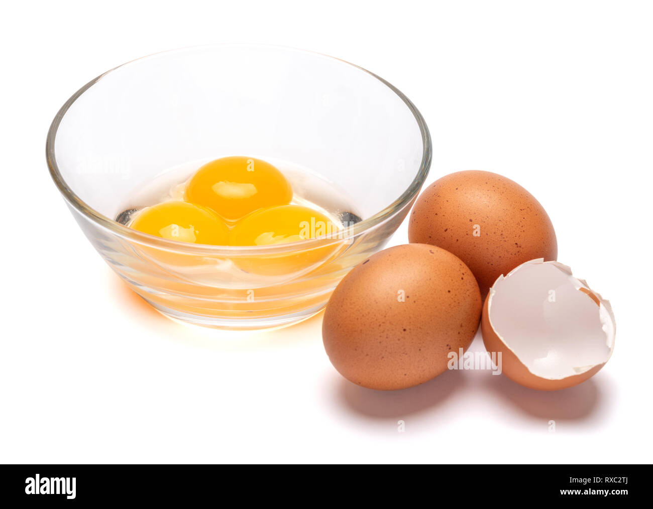 three egg yolk in a glass bowl and shell isolated on white background ...