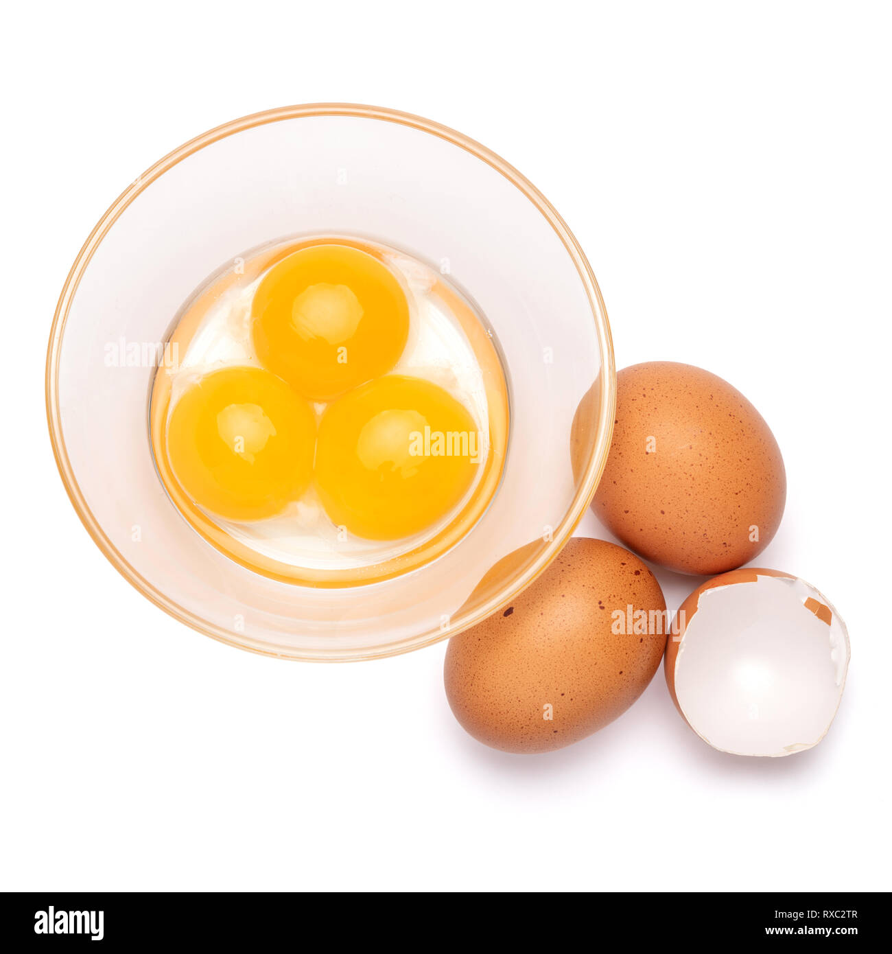 three egg yolk in a glass bowl and shell isolated on white background ...