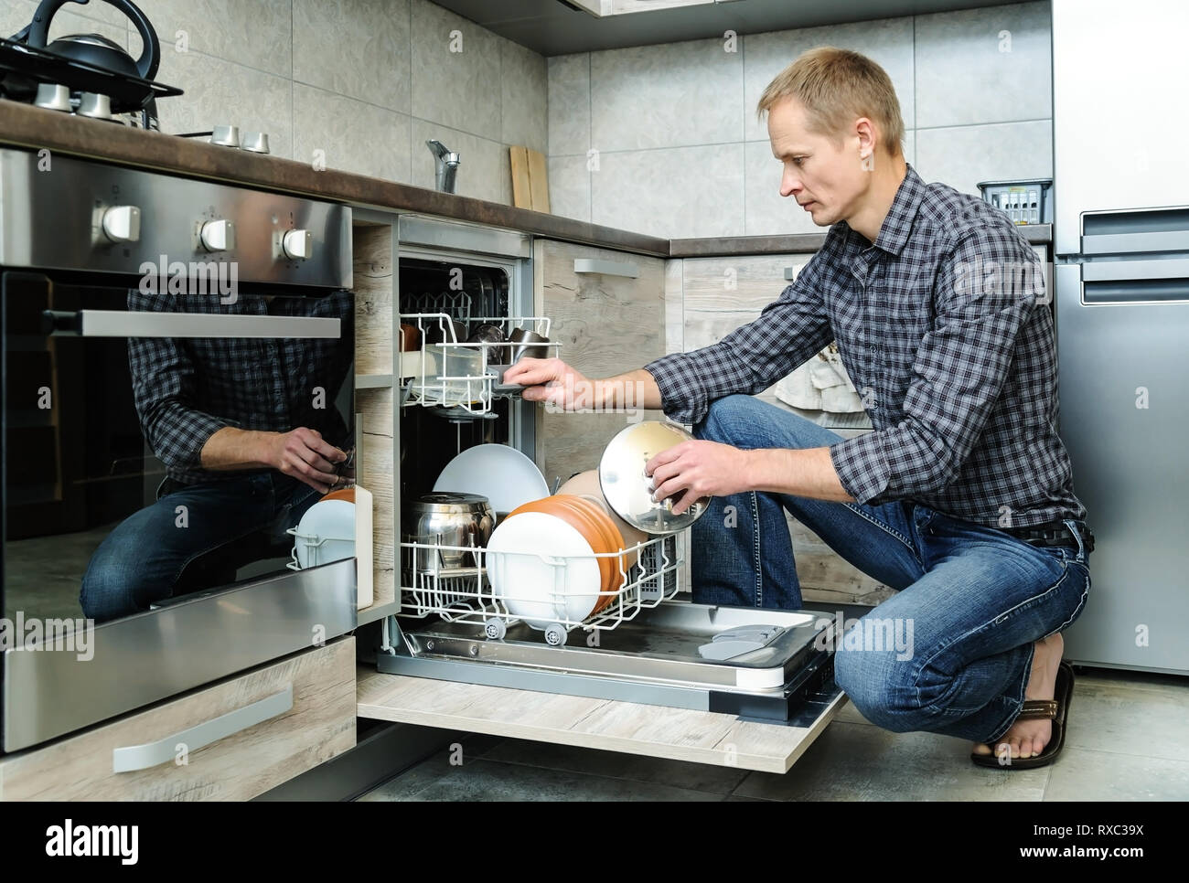 The man pushed the dirty dishes in the dishwashing machine Stock Photo ...
